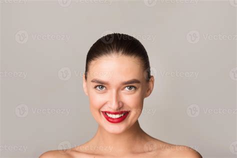 A Beautiful Half Naked Woman Showcasing Red Lipstick On A Neutral Gray