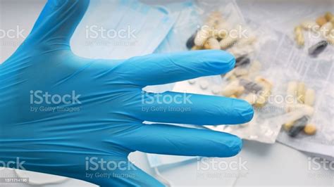 수술 용 장갑의 클로즈업이 입고 간호사가 작업 교대근무를 준비하고 파란색 라텍스 장갑을 착용하고 알약 형태의 약물 팩이 테이블에