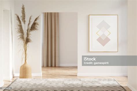수직 포스터가 있는 베이지색 홀 의 내부 출입구 사이에 고리버들 꽃병에 있는 팜파스 잔디 쪽모이 세공 마룻바닥의 카펫 창문이 있는 방이 내려다보입니다 가정의 방에 대한 스톡