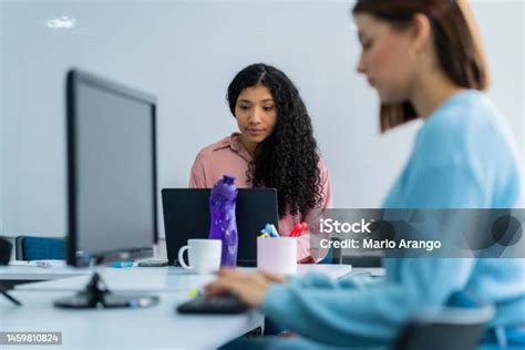 세 명의 라틴 여성이 사무실 안에서 노트북을 사용하여 아이디어를 공유하기 위해 팀워크를 하고 있습니다 20 29세에 대한 스톡 사진 및 기타 이미지 Istock