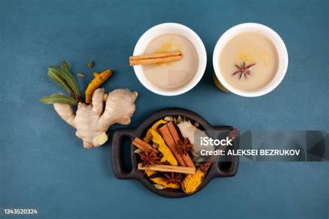 인기 있는 인도 음료 카라크 차 또는 마살라 차이 우유 다양한 향신료와 향신료를 첨가하여 준비했습니다 상단 보기 파란색 배경