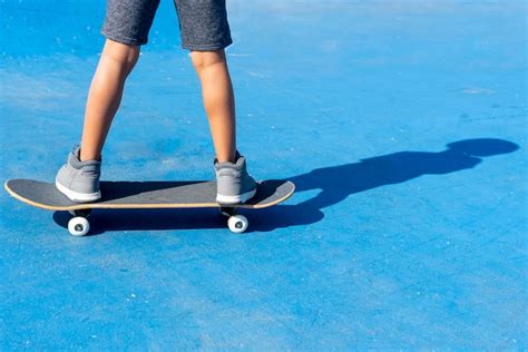 Cerca De Las Piernas De Un Niño En Una Patineta Que Muestra La Sombra