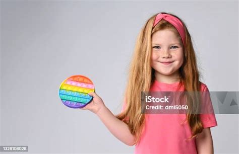 귀여운 분홍색 티셔츠에 미소 아이 소녀 시연 그녀의 새로운 트렌디 한 감각 장난감 무지개 색상 라운드를 보여줍니다 팝 그것 산만함에 대한 스톡 사진 및 기타 이미지 Istock