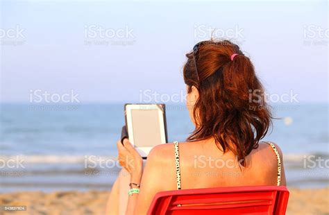 빨간 의자에 예쁜 여자는 전자 책을 읽습니다 갑판 의자에 대한 스톡 사진 및 기타 이미지 갑판 의자 디지털 태블릿 사용하기