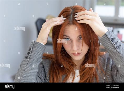 Young Businesswoman With Dyed Red Hair Checking Her Root Regrowth In