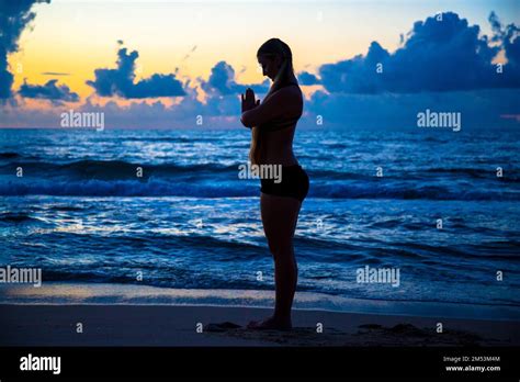 A Caucasian Female On The Beach With The Prayer Pose Pranamasana From