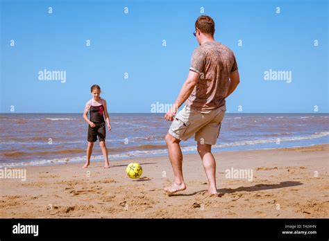 A Father Practices Passing Football With His Teenage Daughter On The