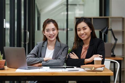 Two Positive Asian Secretary Smiling To Camera During Meeting At Office