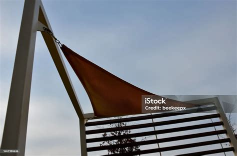 노란 캔버스가 뻗어 있고 태양과 비로부터 그늘이 레스토랑의 테라스 유치원의 놀이터 산책로에 있습니다 나무 회색 빔이있는 퍼 골라