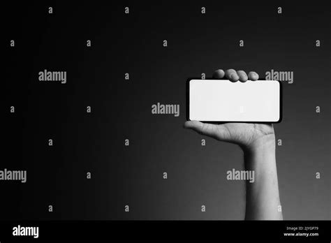 Black And White Image Of Mans Hand Holding Smart Phone Horizontally