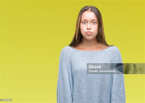 젊은 아름 다운 백인 여자 재미 있은 얼굴 뺨 피 격리 된 배경 위에 겨울 스웨터를 입고 입 어 미친 식으로 팽창 가득 찬에