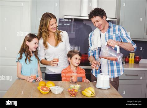 Father pouring fruit juice in glass with family Stock Photo - Alamy
