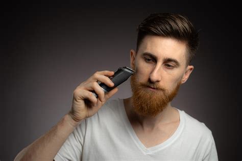 Premium Photo Man Cuts His Beard With A Trimmer