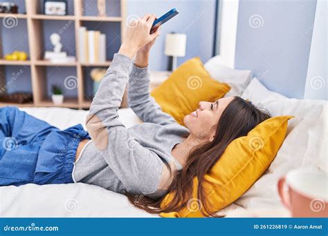 Young Beautiful Hispanic Woman Make Selfie By Smartphone Lying On Bed