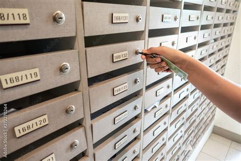 Close Up Of Woman Hand Insert A Key To Unlock Mailbox Locker In Apartment Interior Mail
