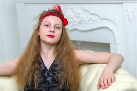 Beautiful Young Girl Sitting On The Sofa By The Fireplace Stock Image