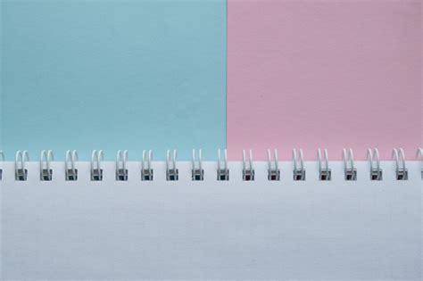 파란색과 파스텔 로즈 핑크 상단보기 테이블에 빈 시트와 복사 공간이 있는 미니멀리즘의 투톤 배경에 빈 나선형 노트북을 엽니 다