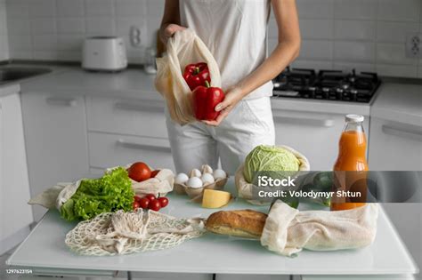 여성의 손은 집에서 부엌에서 채소가 있는 재사용 가능한 식료품 가방을 들고 고추를 꺼냅니다 제로 폐기물 및 플라스틱 무료 개념