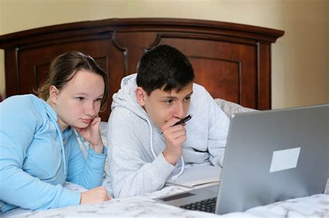 컴퓨터 쌍둥이 형제와 자매 근처에 앉아 온라인 수업을 보고 있는 소년 소녀는 같은 수업에서 공부한다 펜을 들고 있는 소년은 중요한 정보를 적는다 자가격리 영어 강좌 시청 1