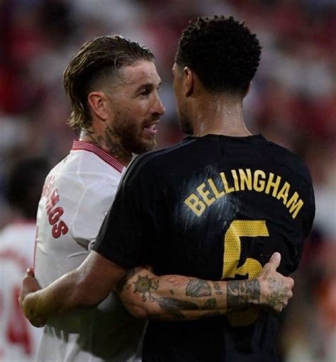 Two Men Standing Next To Each Other On A Soccer Field