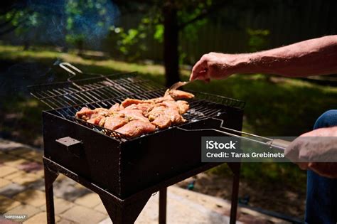 뒤뜰에 있는 바베큐 그릴에서 고기를 요리하는 동안 클로즈업 남성의 손이 포크로 절인 스테이크를 찔렀다 가든파티에 대한 스톡 사진 및 기타 이미지 Istock