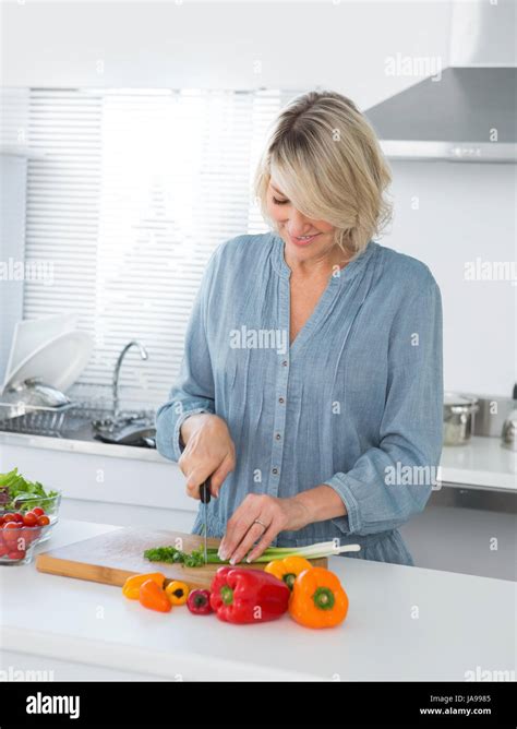 Cheerful Woman Preparing Vegetables At The Kitchen Counter Stock Photo