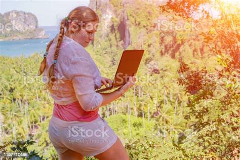 산 꼭대기에서 원격으로 작업 흰색 셔츠에 머리 머리띠와 프리랜서 소녀 그녀는 노트북과 입력 이메일을 보유하고 땋은 머리에 대한
