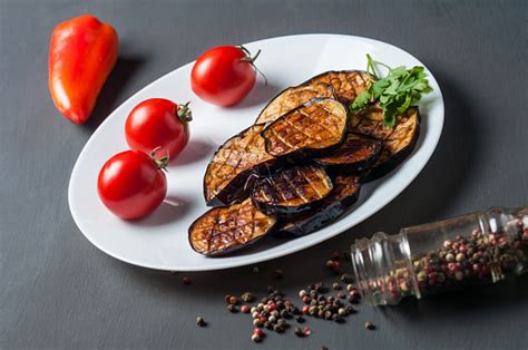 구운 가지 의 조각으로 가득 흰색 세라믹 접시 전체 토마토와 파슬리 흩어져 후추 근처 긁힌 어두운 콘크리트에 거짓말 가지 채소에 대한 스톡 사진 및 기타 이미지 Istock