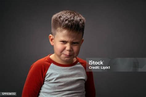 화가 난 소년은 얼굴을 회색 배경에 고립 된 혐오로 보여주는 눈살을 찌푸리고 있습니다 가짜 아이 감정 인간의 감정 얼굴 표정 개념 얼굴 표정 감정 감정 건강 진단에 대한