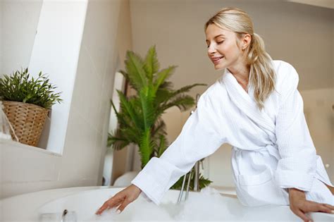 가운을 입은 젊은 예쁜 여자가 자신을 위해 거품으로 뜨거운 목욕을합니다 스파 절차 25 29세에 대한 스톡 사진 및 기타 이미지 25 29세 금발 머리 긍정적인 감정