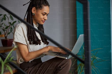 이메일을 쓰는 나무 계단에 앉아 집중된 아름다운 여성의 측면 모습 사진 Unsplash의 실내 이미지