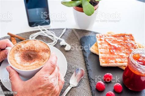 따뜻한 홈메이드 카푸치노와 딸기 잼이 함께 있는 달콤하고 건강한 아침 식사 흰색 테이블에 식물과 휴대 전화 0명에 대한 스톡