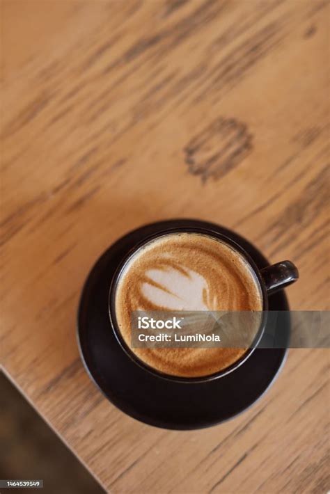 커피 머그잔 라떼는 카페에서 제공되는 프로테아 모양의 꽃 거품이 있는 음료 위의 나무 테이블에 있습니다 레스토랑에서 음료 식당 에스프레소 또는 카푸치노를 아침 아침 또는