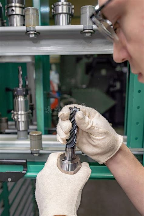 A Worker Inspects And Selects A Cutter From A Rack To Use On A Cnc