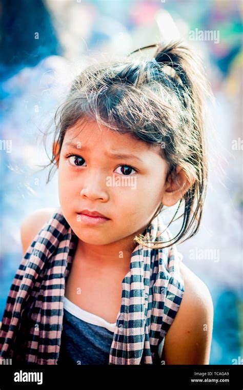 A Shy Cambodian Girl Wearing The Traditional Khmer Scarf Sits Outside A