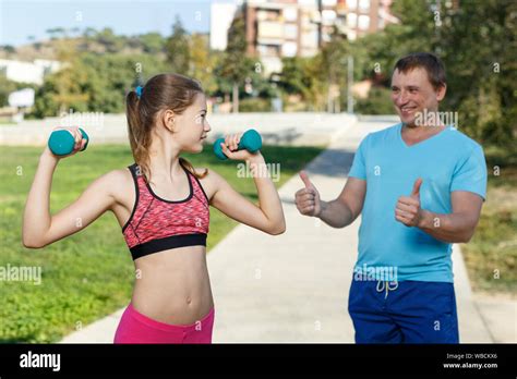 Sporty Preteen Girl Exercising With Dumbbells While Father Controlling