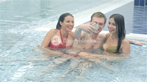 Two Beautiful Women And A Young Man Taking Selfies In The Swimming Pool