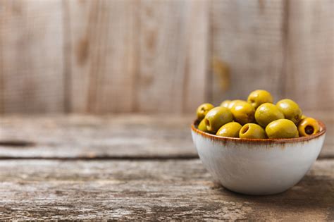 녹색과 검은색 올리브는 질감이 있는 오래된 나무 배경에 그릇에 나뭇잎이 있습니다 맛있고 건강한 음식 진미지중해식 주방 텍스트를 위한 위치입니다 카피스페이스 건강한 생활방식에