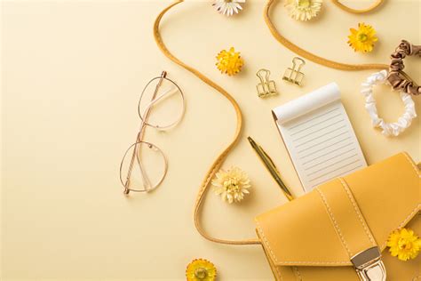 여성의 날 구성 옐로우 가죽 지갑 세련된 안경 의 상단 보기 사진은 카피 스페이스와 고립 된 베이지 색 배경에 노트북 황금 펜