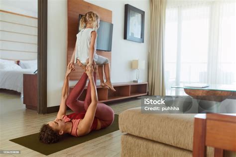 가족 딸과 어머니는 집에서 파트너 요가를 연습 청녀와 자녀가 함께 운동한다 거실에서 아크로요가를하는 스포티 한 부모와 아이 2