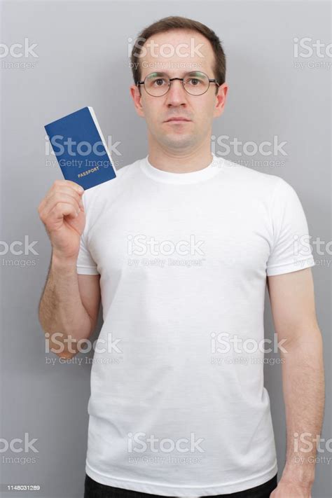 그의 손에 여권을 가진 유럽 남자 안경을 쓰고 흰색 T 셔츠 여권 국가의 시민 남자와 함께 스튜디오 사진 T 셔츠에 대한 스톡 사진 및 기타 이미지 Istock