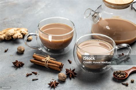 인도 마살라 차이 티 우유와 향신료가 들어간 뜨거운 Masala Chai 매운 차가 회색 배경의 유리 유리에 부어집니다 긴 배너