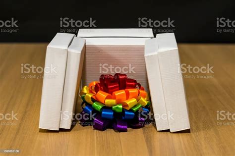 선물 구성입니다 다양 한 색상의 줄무늬와 함께 상자 다 색된 활입니다 흰색 상자 주변을 확인 하 고 있습니다 나무 테이블입니다
