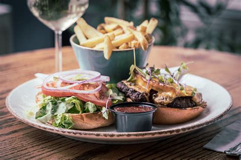 나무 테이블 표면에 원형 접시에 빵 감자 튀김 소스를 곁들인 치즈 버거 와인잔이 있는 펍 또는 레스토랑에서 제공 레스토랑에 대한 스톡 사진 및 기타 이미지 Istock