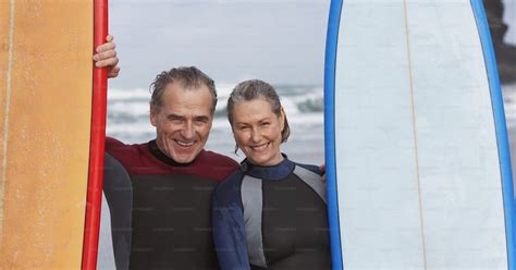 서핑보드를 들고 나란히 서 있는 남자와 여자 사진 Unsplash의 바다 이미지