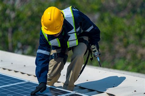 두 명의 엔지니어가 안전 장비와 헬멧을 착용하고 옥상에 태양 전지판을 설치합니다 맑고 푸른 하늘 아래 재생 에너지 친환경 기술 지속 가능한 솔루션을 보여주는 장면입니다 건설