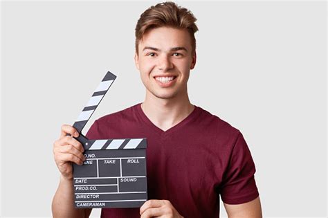 광범위 한 미소와 쾌활 한 남성 캐주얼 티셔츠를 착용 보유 Clapperboard 흰색 배경 위에 절연 창조 새로운 영화에 참가