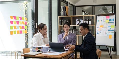 Group Of Young Asian Business People Brainstorming Looking At Laptop