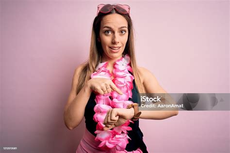 젊은 아름다운 금발의 여자 수영복과 꽃 하와이 레이 를 입고 분홍색 배경 에 서둘러 가리키는 시계 시간 조바심 화가 마감 지연에