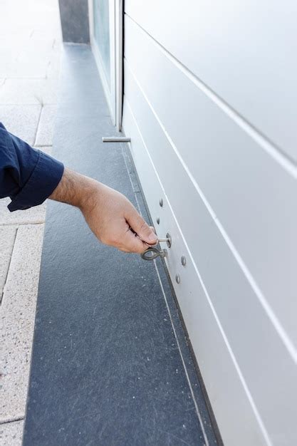 Premium Photo Hand With A Key Closing A Roller Shutter Door Of A